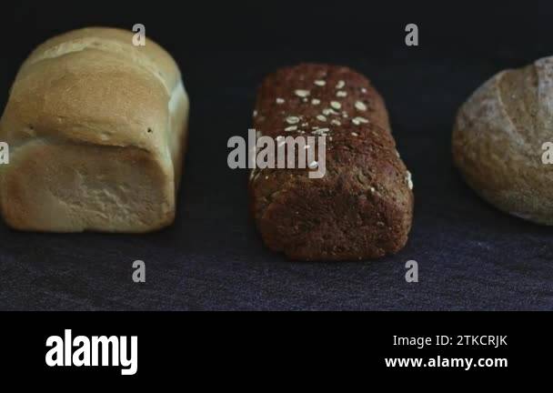 Three loaves of different varieties, sizes and shapes lie on a black ...