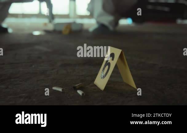 Close-up shot of yellow police marker with number 6 on ground next to ...