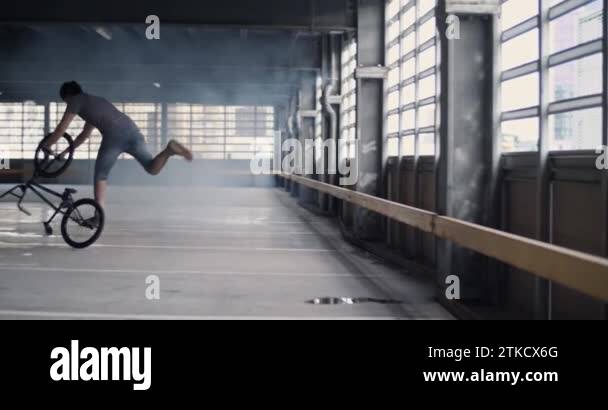 Real time handheld shot of young sportive guy riding on rear wheel of ...