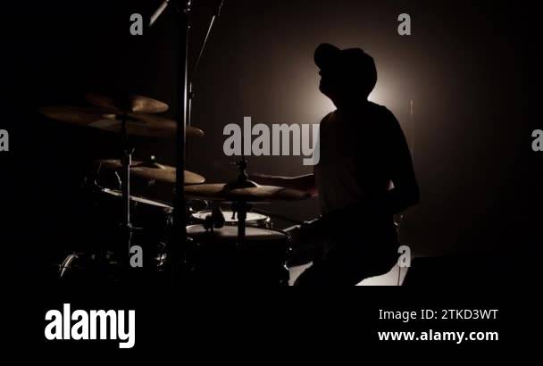 Silhouette of faceless male drummer playing beat on professional drum ...