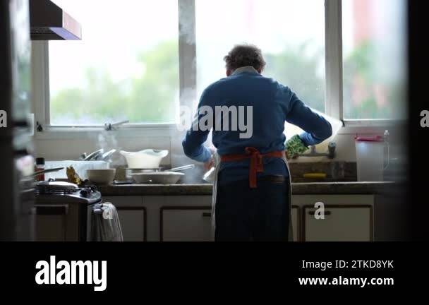 Candid senior chef cook standing by kitchen counter preparing meal ...