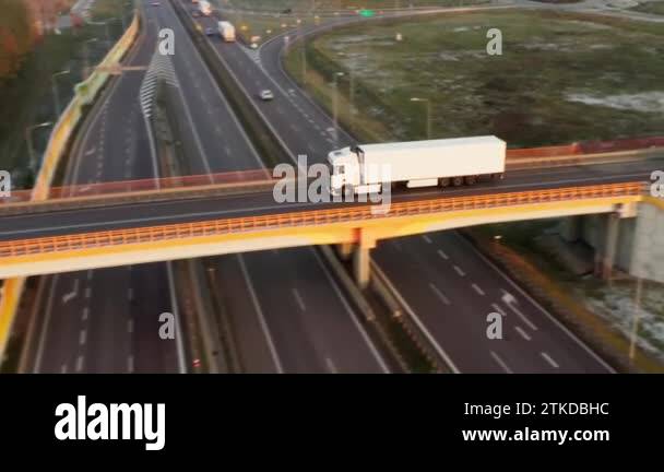A white truck with a trailer drives over a bridge crossing an ...