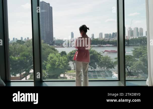 A woman with a visionary stands by a vast window, contemplating the ...