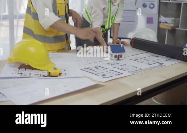 Team of engineers working together on blueprint plan at construction ...