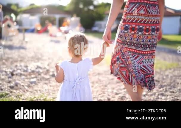 Little girl learns to walk by stumbling and holding her mother finger ...