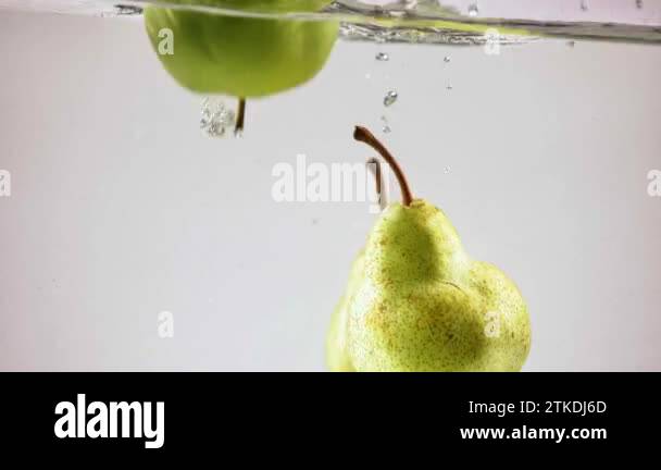 Green apples and pears, delicious fruits falling into water. Bubbles ...