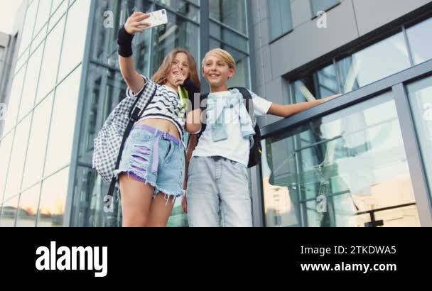 Cute funny small teens boy and girl standing near school building with ...