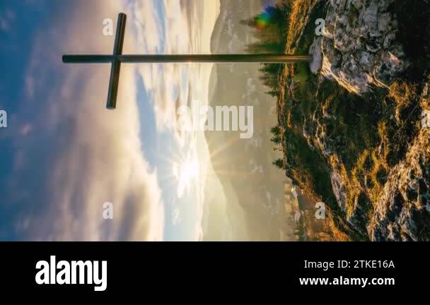Vertical video of Beautiful Sunset over steel cross in top of rocky ...