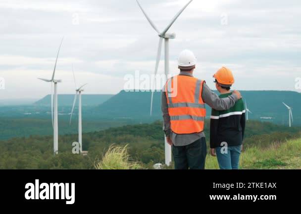 Engineer with his son on a wind farm atop a hill or mountain in the ...