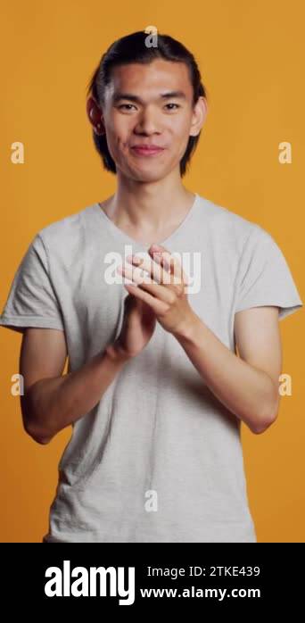 Vertical video: Smiling person clapping hands in studio, laughing and ...