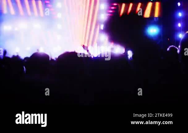 People clap their hands and dance at evening concert with light show ...