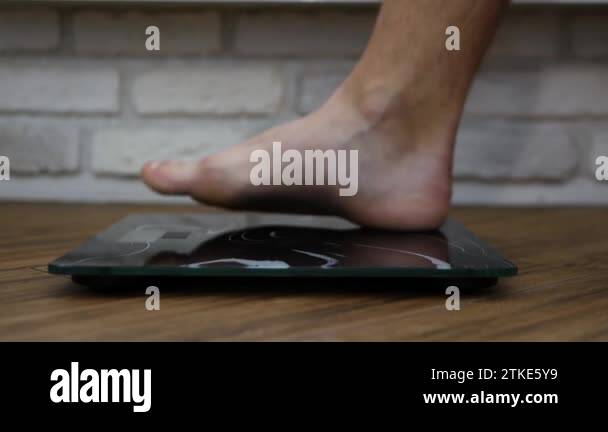 Barefoot men's feet stand on the floor scales against the background of ...