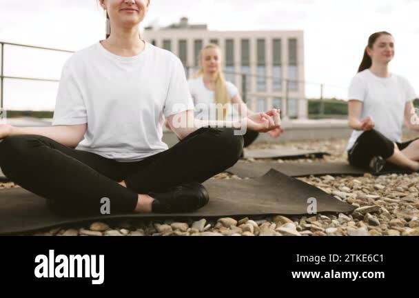 Cropped view of young females in sports clothes breathing in half lotus ...