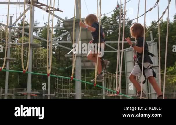 Two brothers boldly navigate obstacles in a rope park, strengthening ...