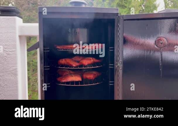 Open smoker with finished smoked salmon trout fillet on racks ready to ...