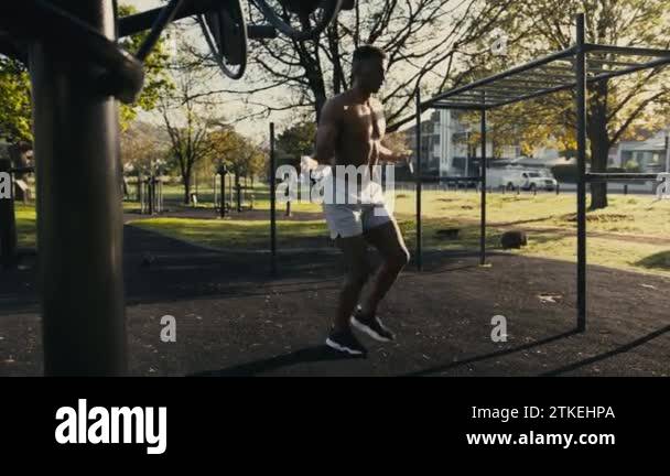 Shirtless muscular young black man skipping with skipping rope next to ...