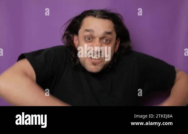 Young handsome punk guy shakes his long hair and shows the goat sign ...