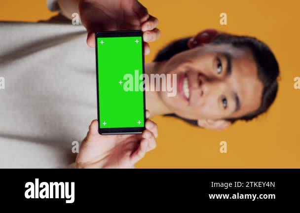 Vertical video: Male model holding horizontal greenscreen mobile phone ...