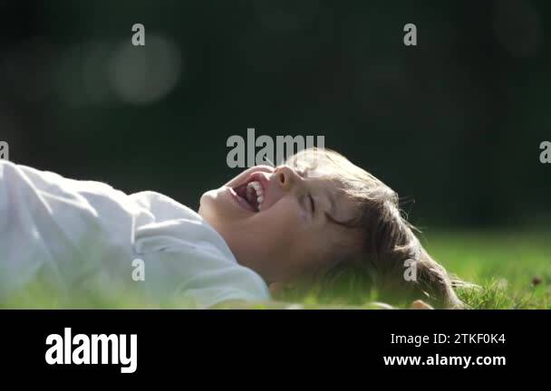 Tickling one happy young boy lying on grass outside. Closeup face of ...