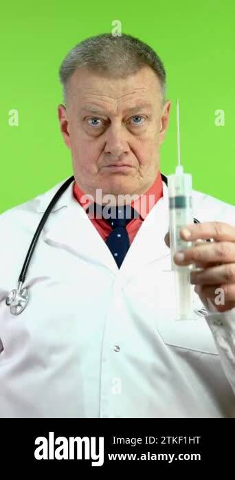 Senior angry doctor threatens with his clenched fist and large syringe ...