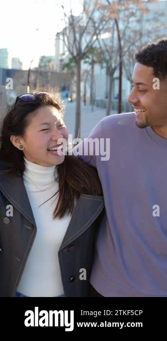 Happy diverse young friends walking together hugging each other outdoors. Multiethnic group of ...