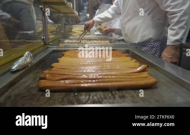 Close-up of a cooks hand frying Bavarian sausages in the evening at a ...