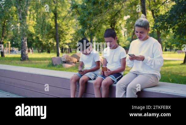 Smartphone addiction. Asian family - mother and two sons sit buried in ...