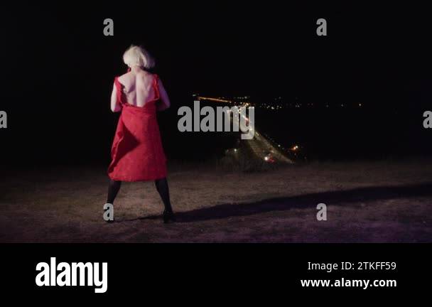 Extravagant drag queen in red dress lifts up her skirt and shows her ...