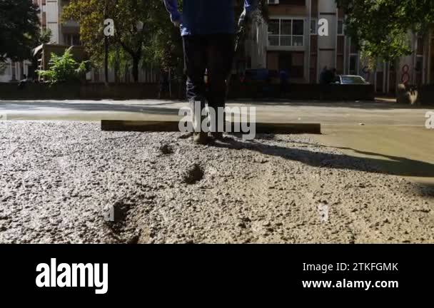 Construction worker is leveling fresh concrete with motor power tool ...