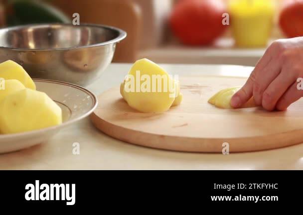 The process of cutting potatoes. A woman cuts potatoes with a knife on ...