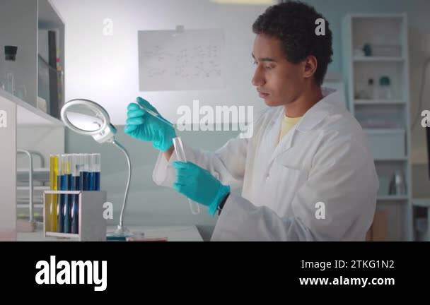 Side view waist up shot of young Biracial male scientist in white lab ...