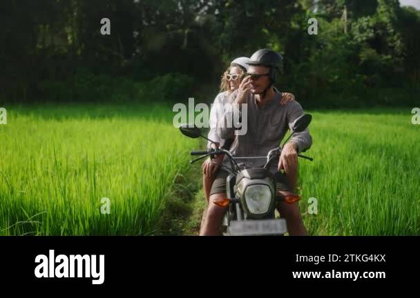 Couple talk sitting on motorbike in rice field. Man, woman in love ride ...
