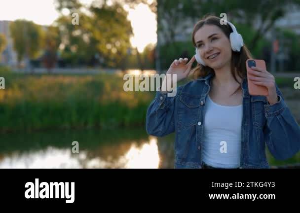 Happy caucasian woman listening to music from the headphones, holding ...