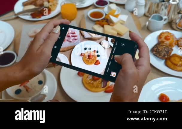 Female influencer and blogger captures breakfast on phone camera. Takes ...
