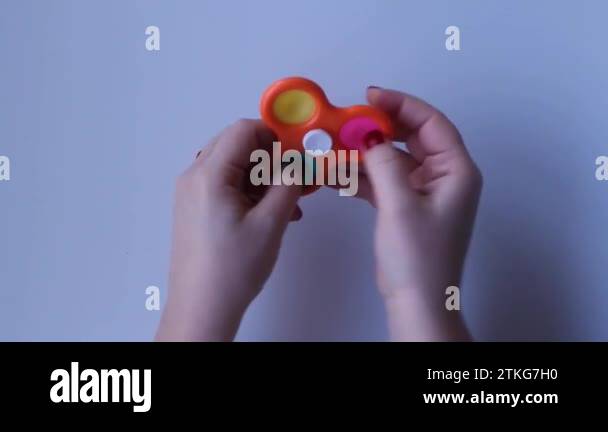 Women hands crumple and play with spinner Pop It close-up top view ...