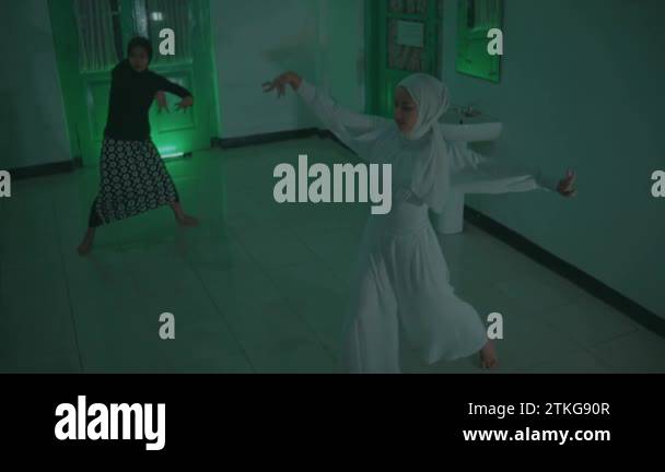 two Muslim women dance together very agilely in closed clothes in a ...