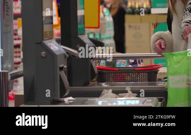 female buyer using self-service cashier checkout in supermarket ...