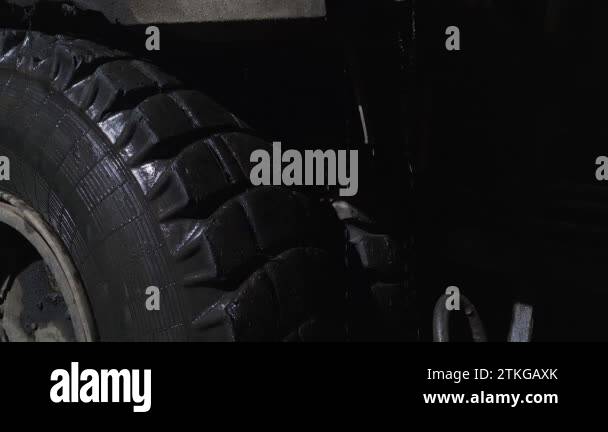 Tyre of big industrial truck wheel, water drops and steam at night ...