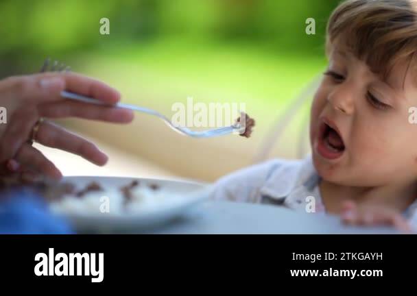 Feeding child food. Funny scene of mischievous little boy taking a bite ...