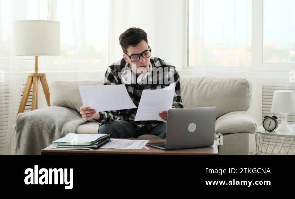 In the office setting, a young man meticulously sorts through work ...