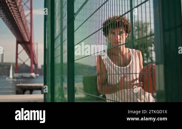 Curly teenager posing metal grid portrait. Basketball player looking ...