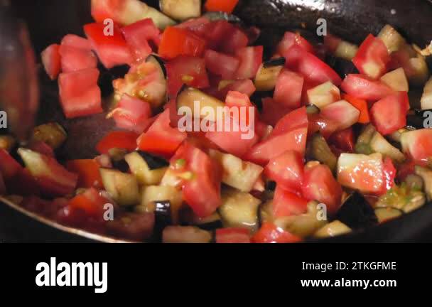Cooking roasted vegetables. Chef stirs with spoon into steaming hot pan ...