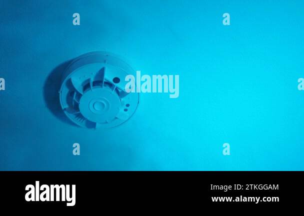 The smoke detector is mounted on the ceiling and the smoke rising ...