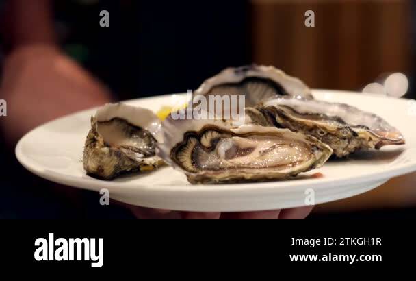 Man enjoying fresh oysters with lemon juice in luxury restaurant. Male ...