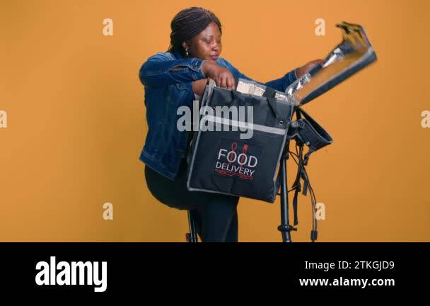 Young african american woman removing pizza box from food delivery bag ...