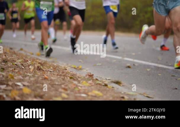 Slow motion unrecognizable athletes running marathon on road with ...