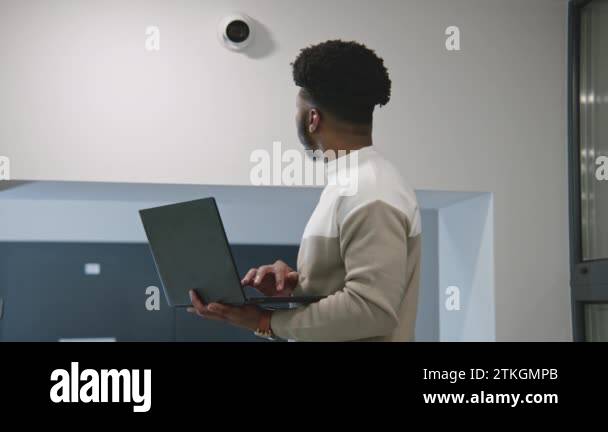 African american installer sets up security camera in office room using ...