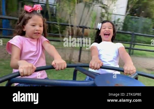 2 fun little girl playing at playground roundabout carousel in motion ...