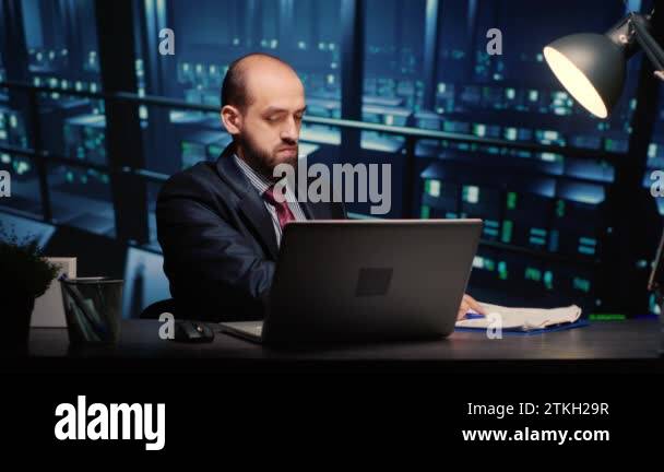 Male infrastructure engineer working in render farm running diagnostics on mainframe computer ...