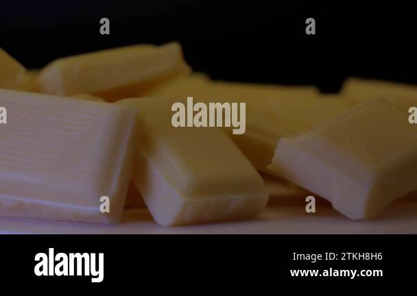rotation of white chocolate bar pieces picked up by the fingers of a ...